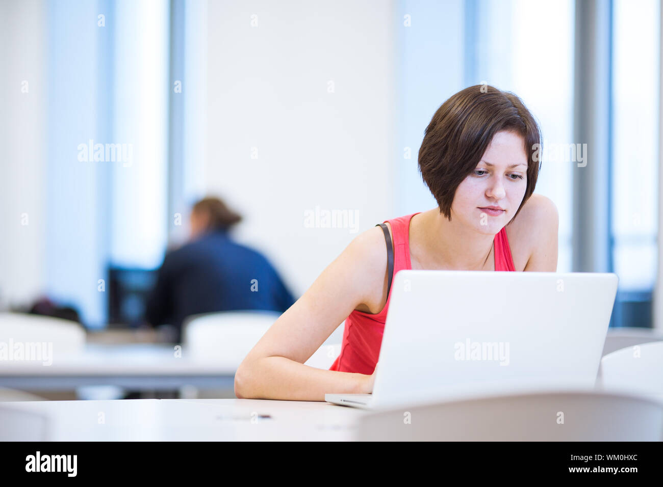 Pretty, young college student studying in the library/a study room at ...
