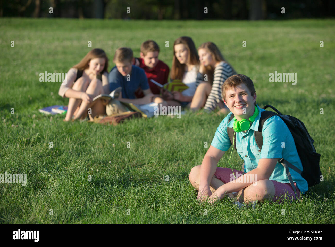 Confident male teen student with backpack sitting outdoors Stock Photo ...