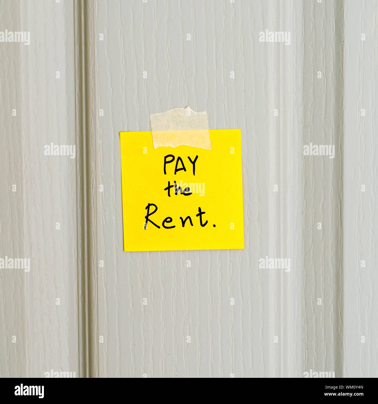 sticky note write a message pay the rent on wood door background Stock ...