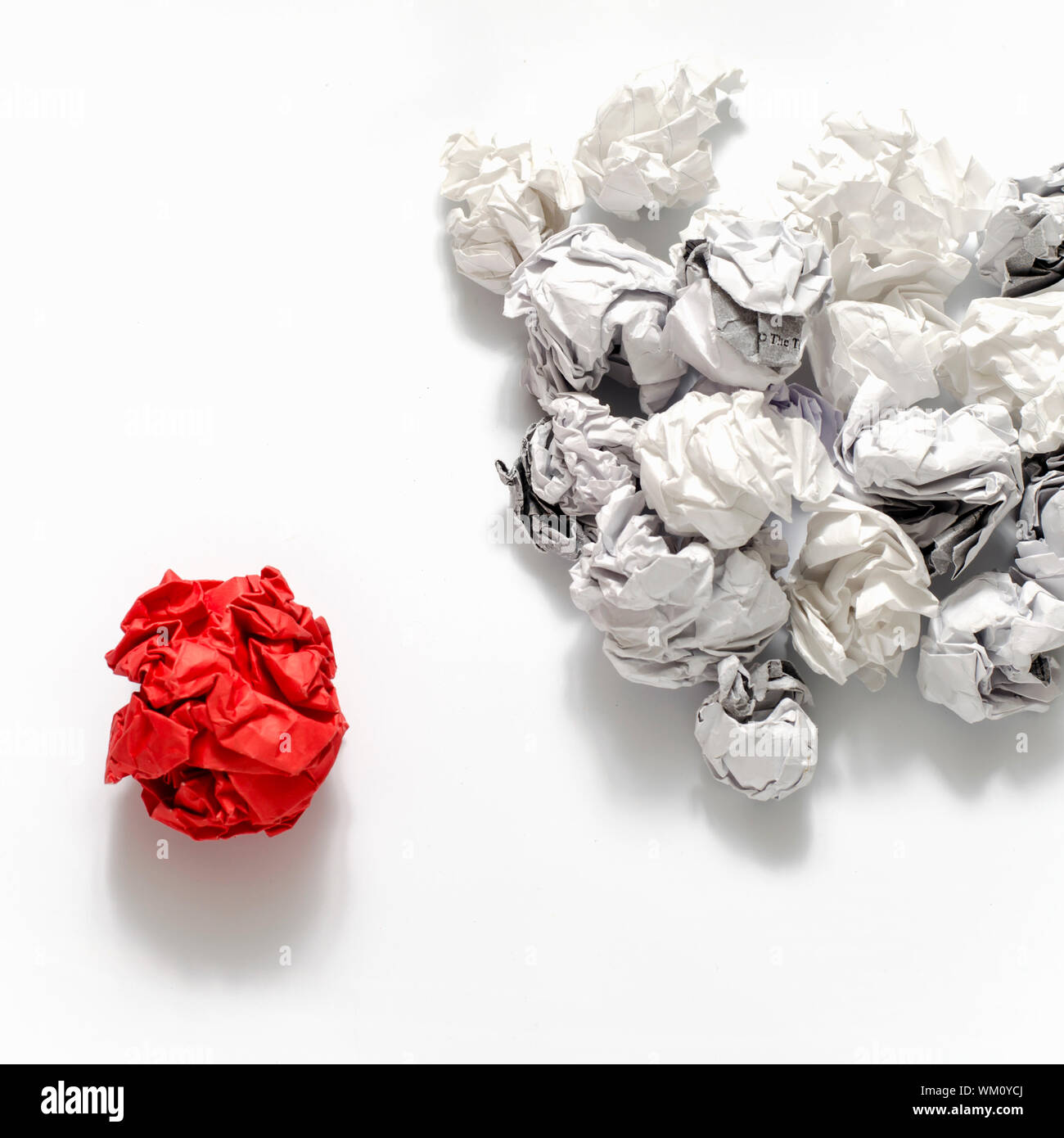 white crumpled paper ball and different red crumpled paper ball on a ...
