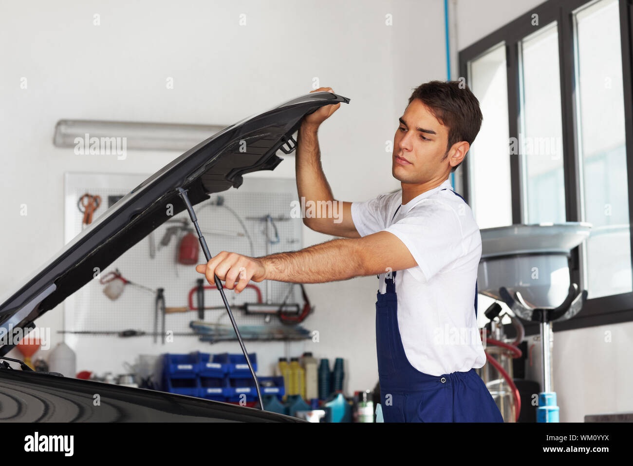 Male mechanic opening car bonnet. Side view Stock Photo - Alamy