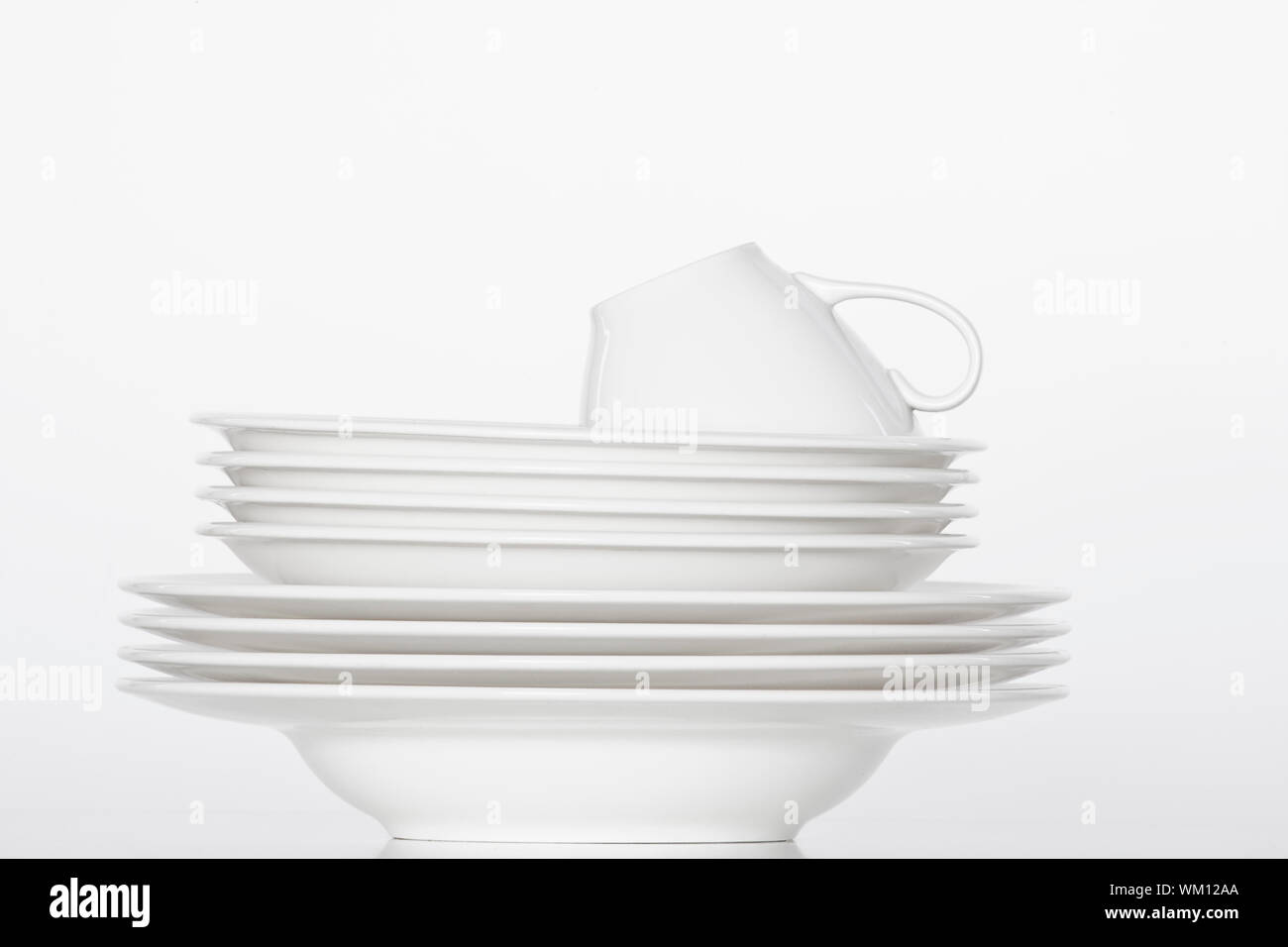 studio shot of a pile of white plates and white cup isolated on white ...