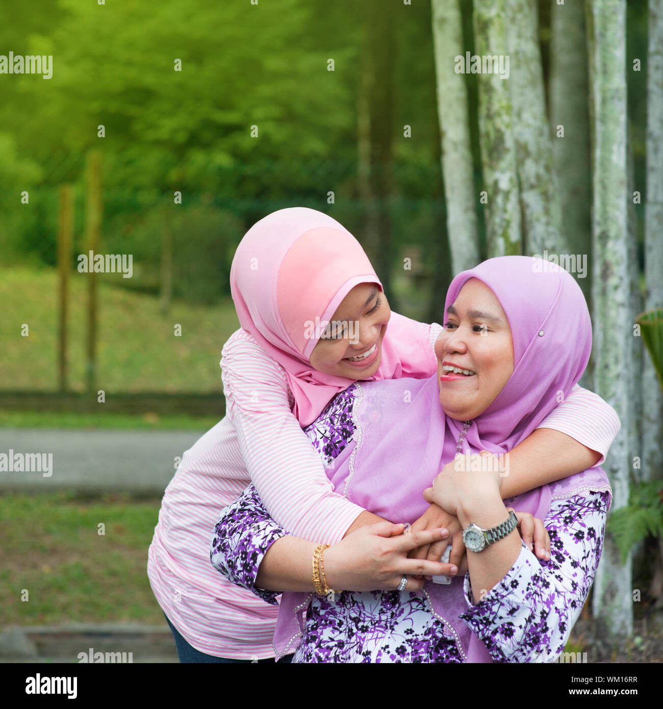 Happy Southeast Asian Muslim mother and daughter at outdoor park ...