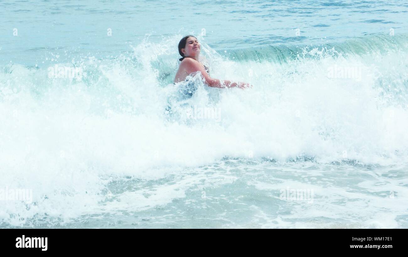 Full Length Of Woman Jumping In Wave In Sea Stock Photo - Alamy