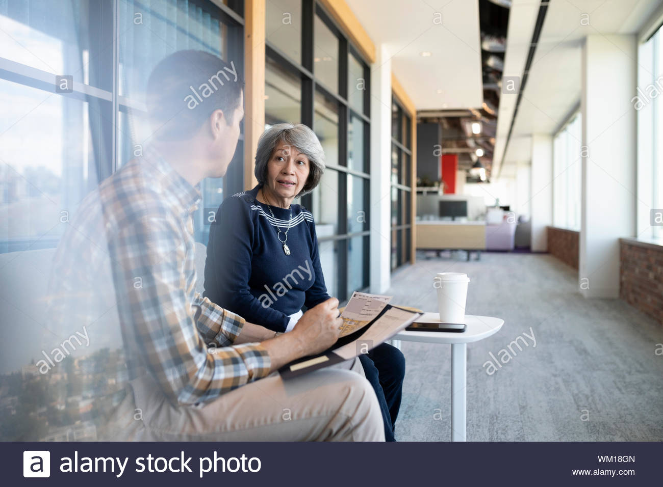 Man sitting in hospital corridor with mother completing paperwork Stock ...