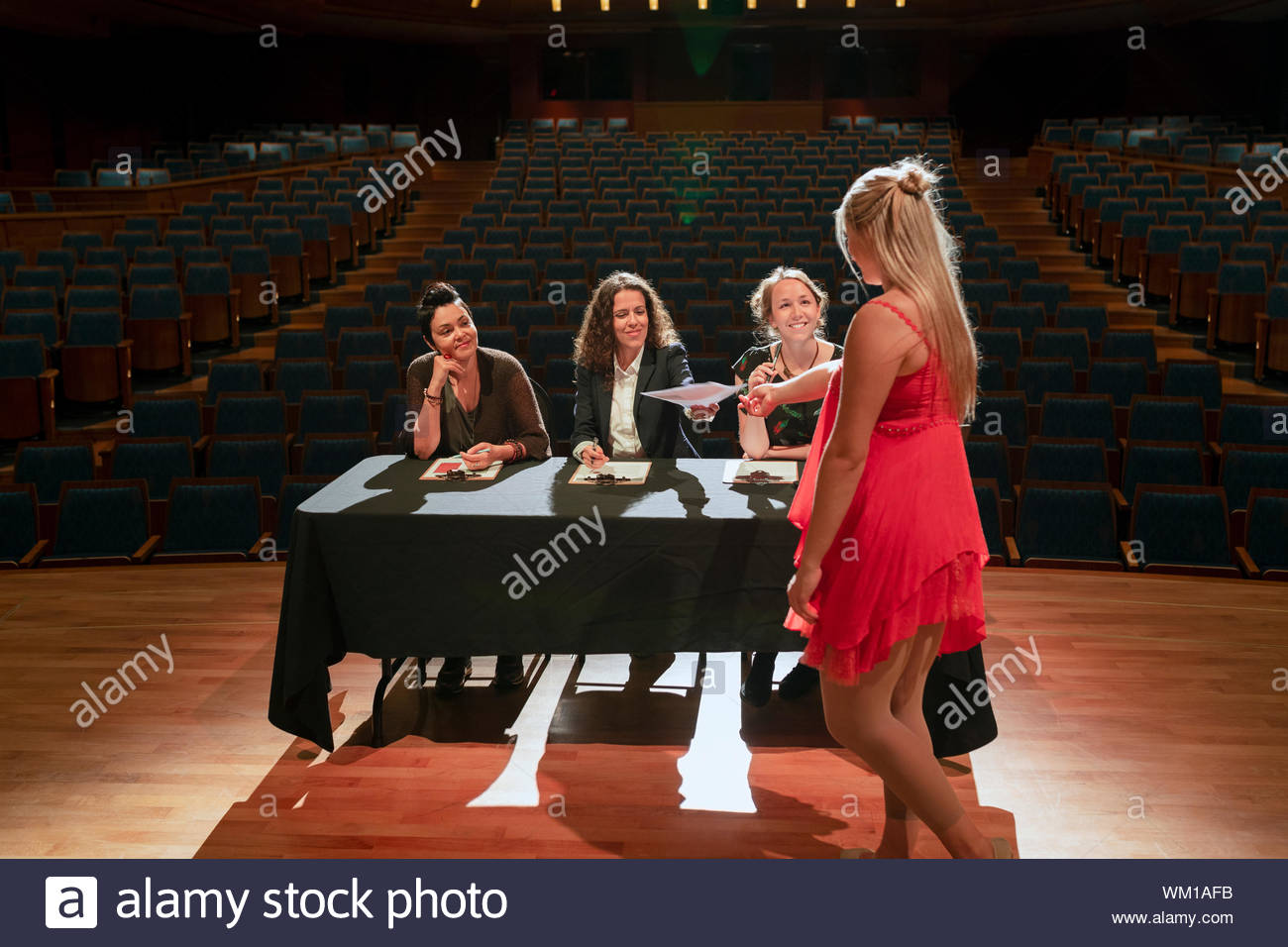 Female judges greeting dancer on stage in auditorium Stock Photo - Alamy