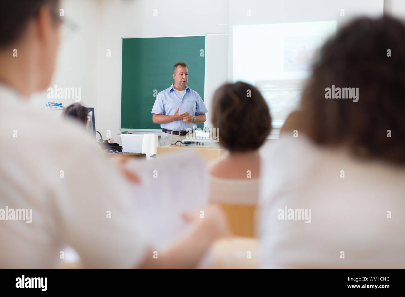 Teacher at university in front of a whiteboard screen. Students ...