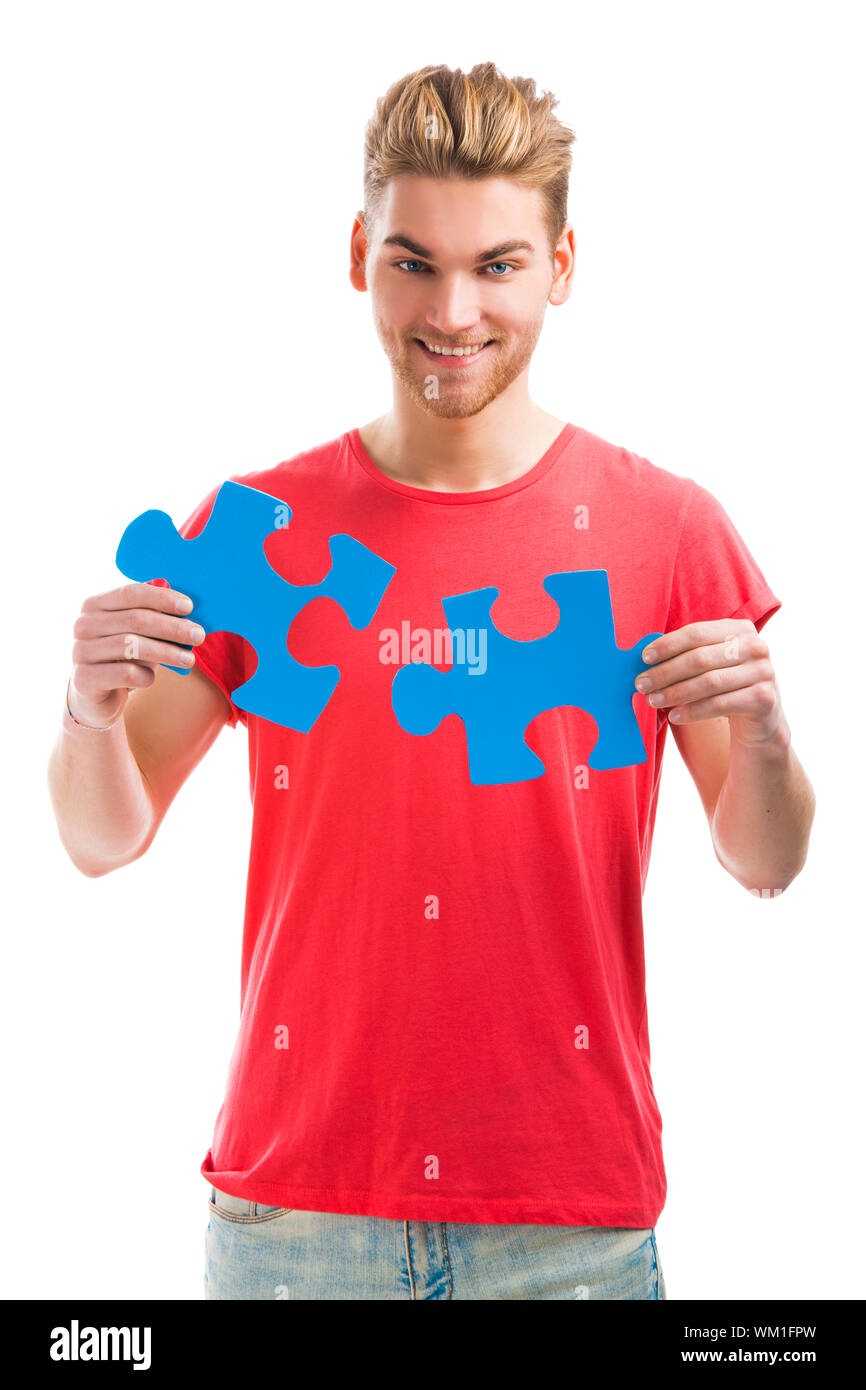 Good looking young man holding a blue puzzle piece, isolated on a white ...