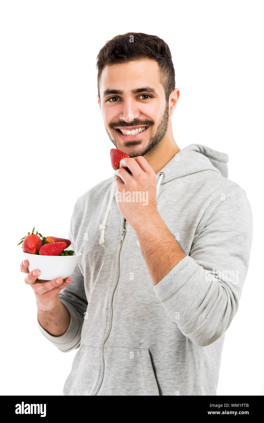 Happy young man eating a strawberry, isolated on white background Stock ...
