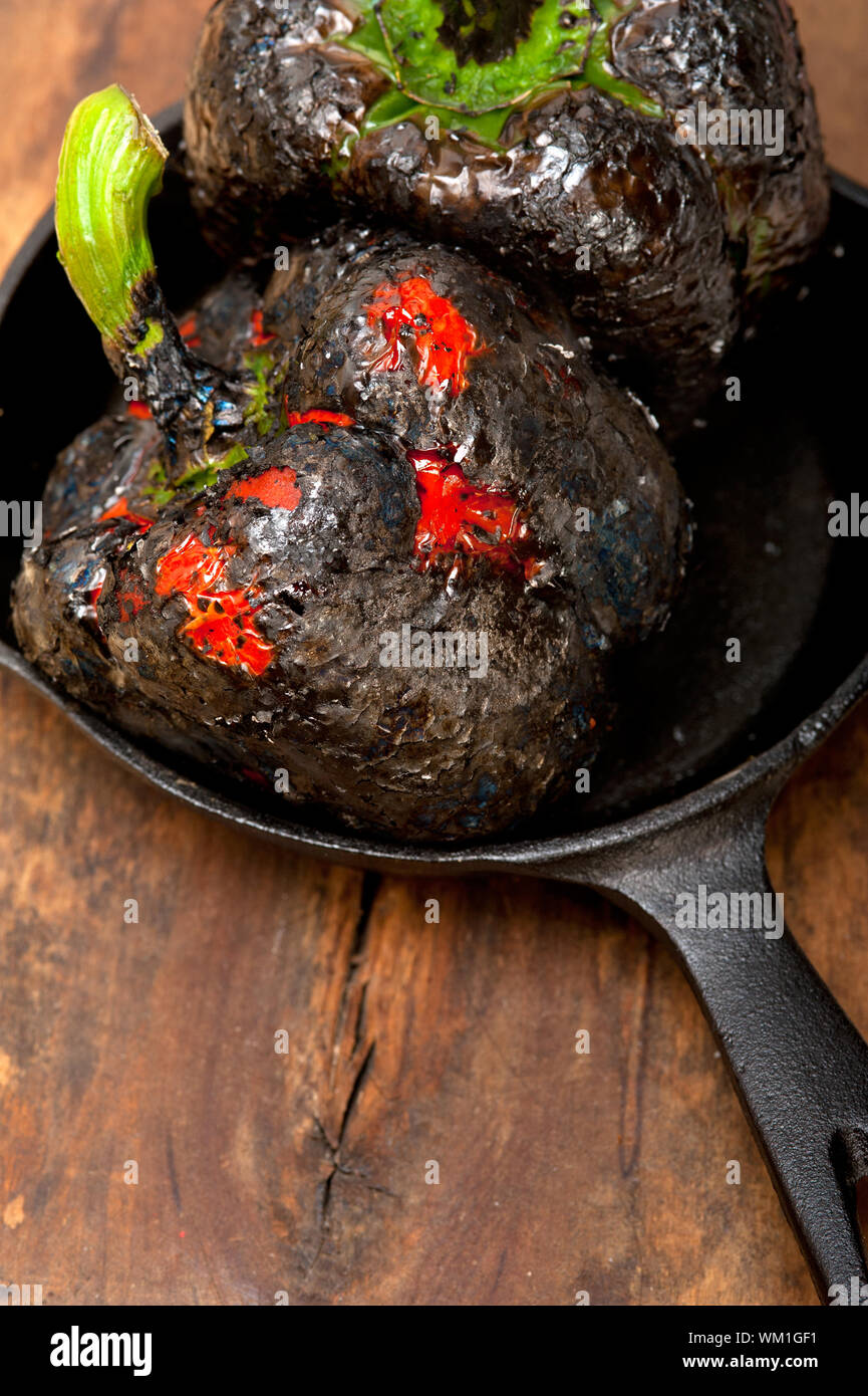 three fresh bell peppers charcol scorched over old wood table on a ...