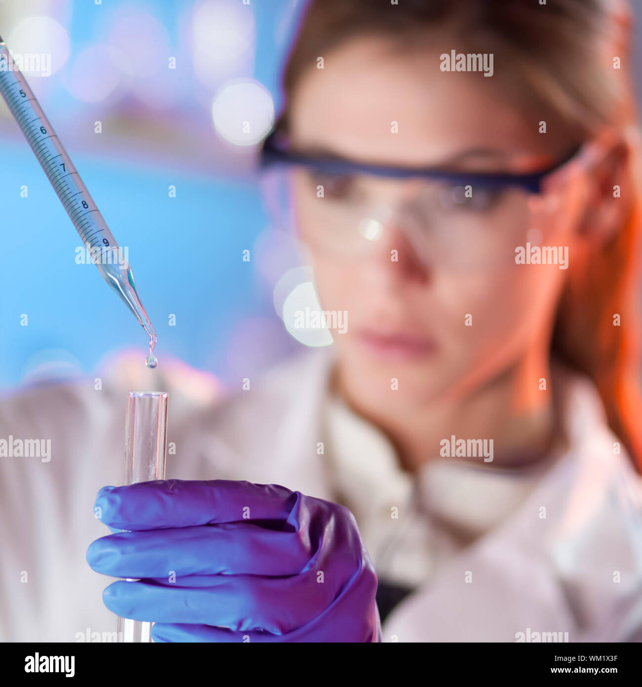 Focused life science professional pipetting solution into the glass ...