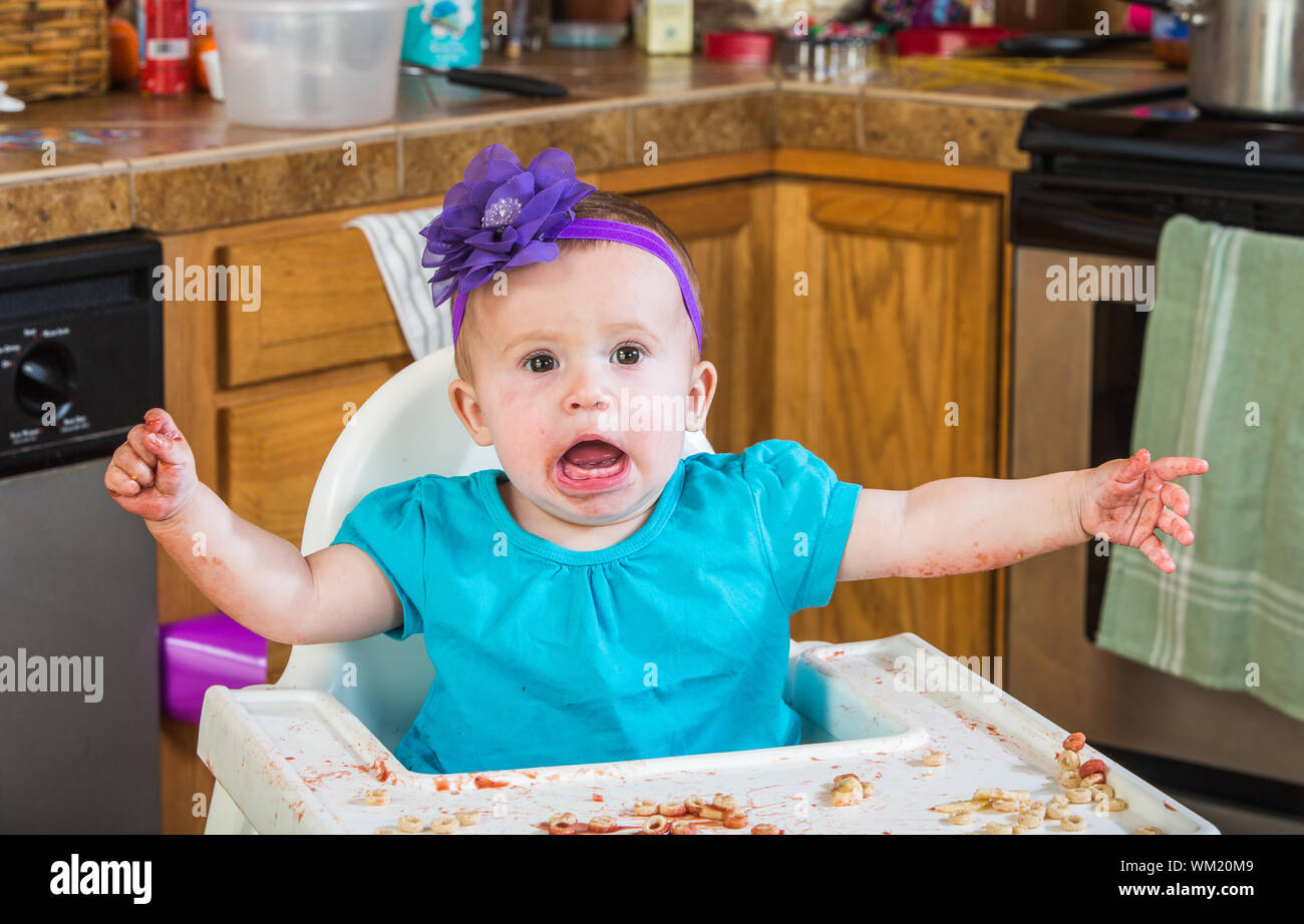 A talkative baby girl eating in the kitchen Stock Photo - Alamy