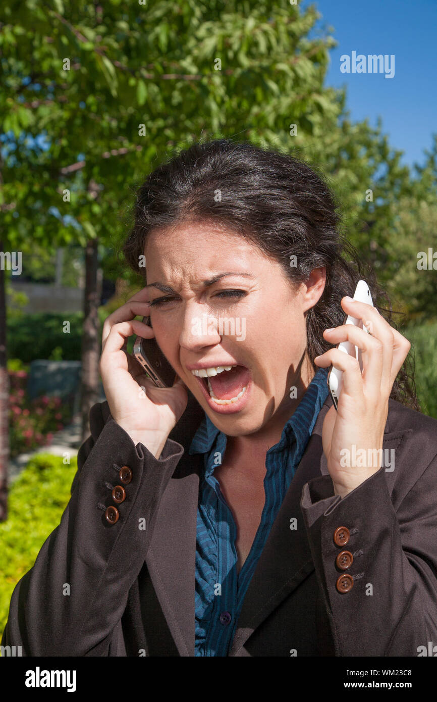 anger woman shouting with two mobiles in exterior Stock Photo - Alamy