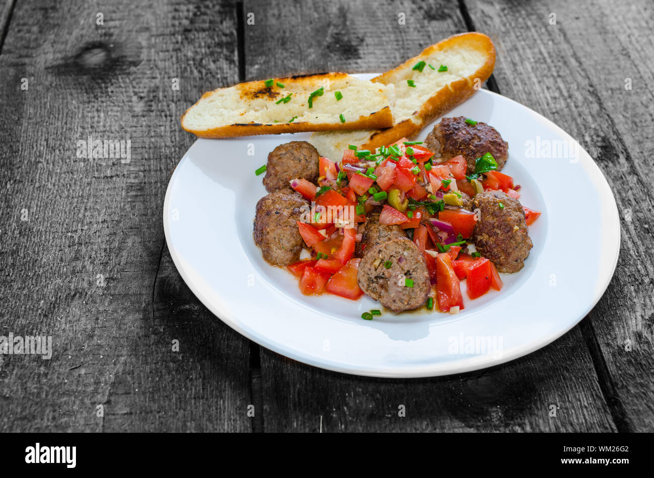 Meatballs with spicy tomato salsa, baked baguette and basil on top ...
