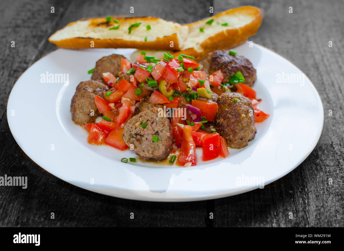 Meatballs with spicy tomato salsa, baked baguette and basil on top ...