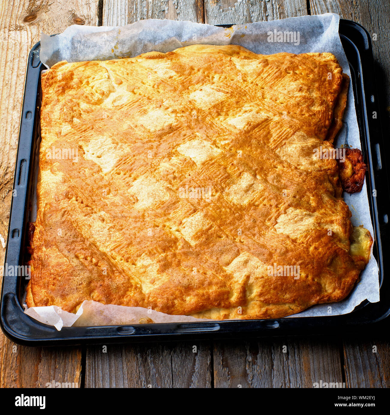 Homemade Closed Cheese Pie on Black Oven with Parchment Paper closeup ...