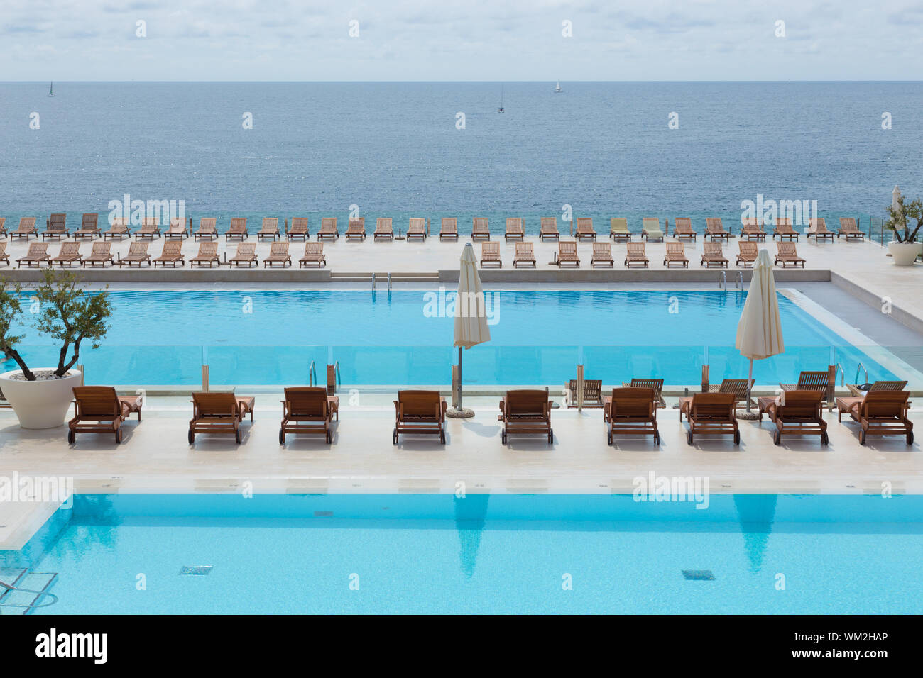 Turquoise swimming pool with modern wooden sunbeds Stock Photo - Alamy