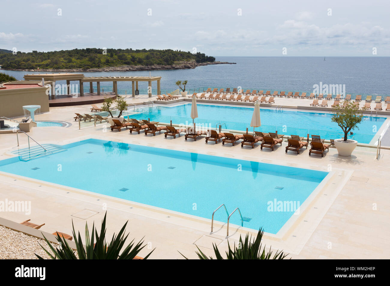 Turquoise swimming pool with modern wooden sunbeds Stock Photo - Alamy