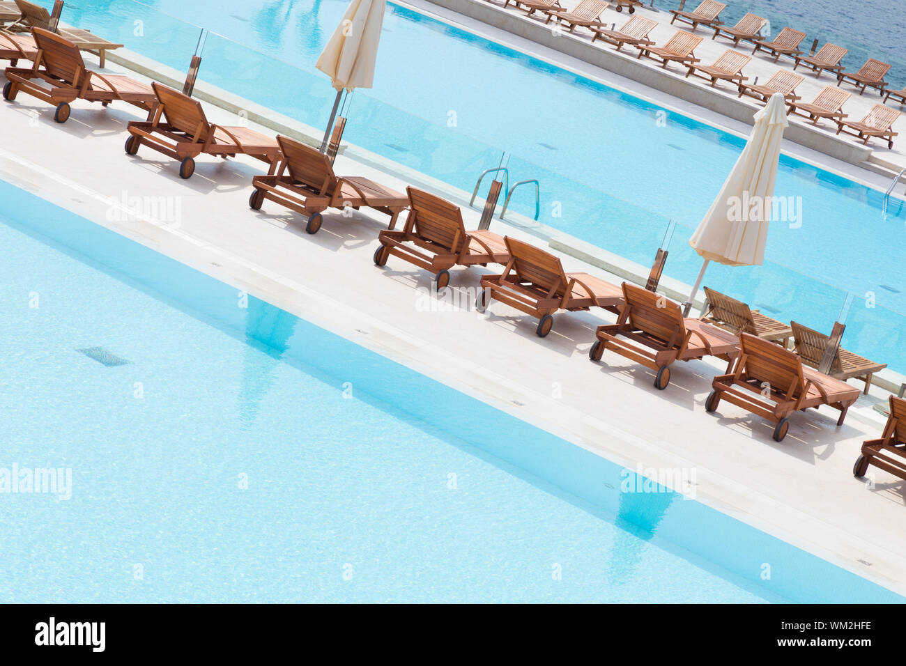 Turquoise swimming pool with modern wooden sunbeds Stock Photo - Alamy