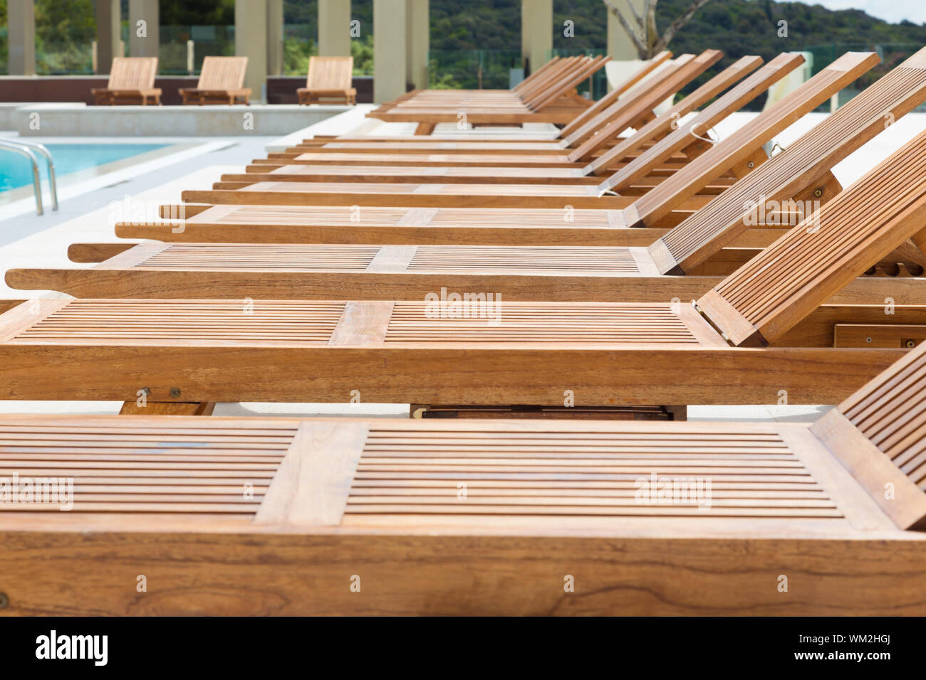Swimming pool with wooden sunbeds Stock Photo - Alamy