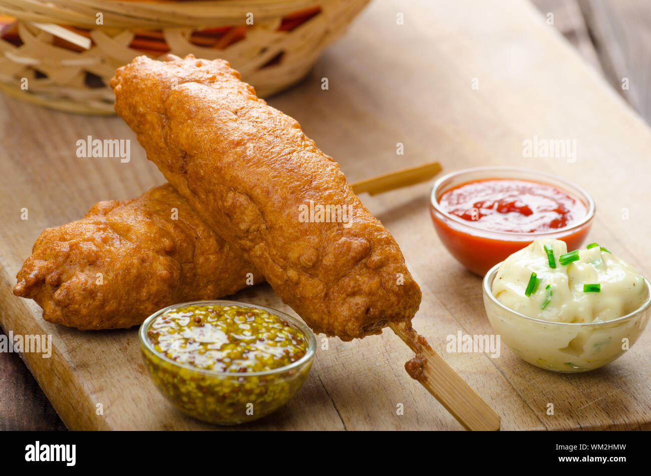 Corn dog with three sauces, chilli, mayonnaise with herbs and whole ...