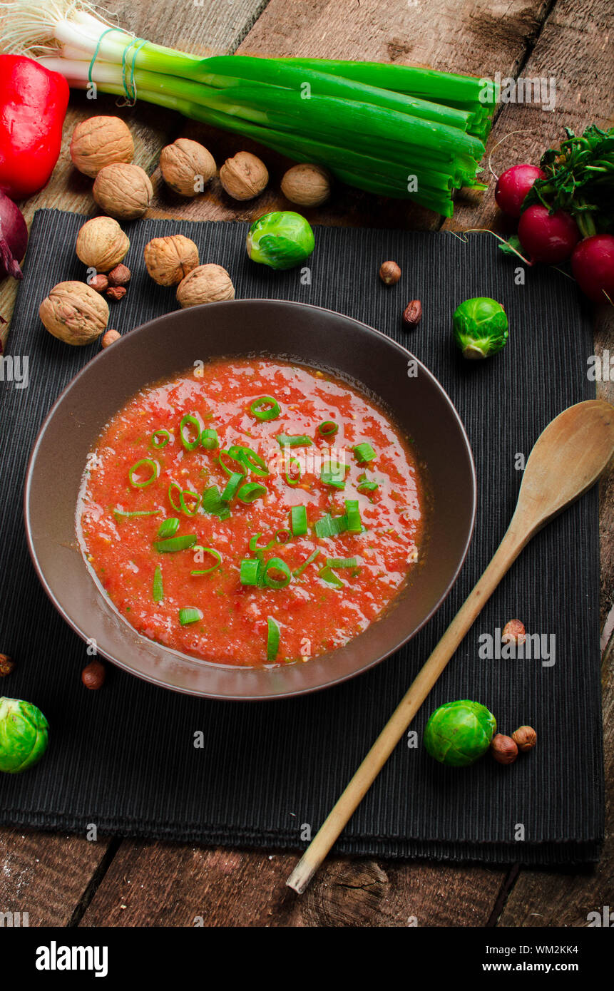Hot salsa tomato with spring onion and red pepper on wood plate with ...