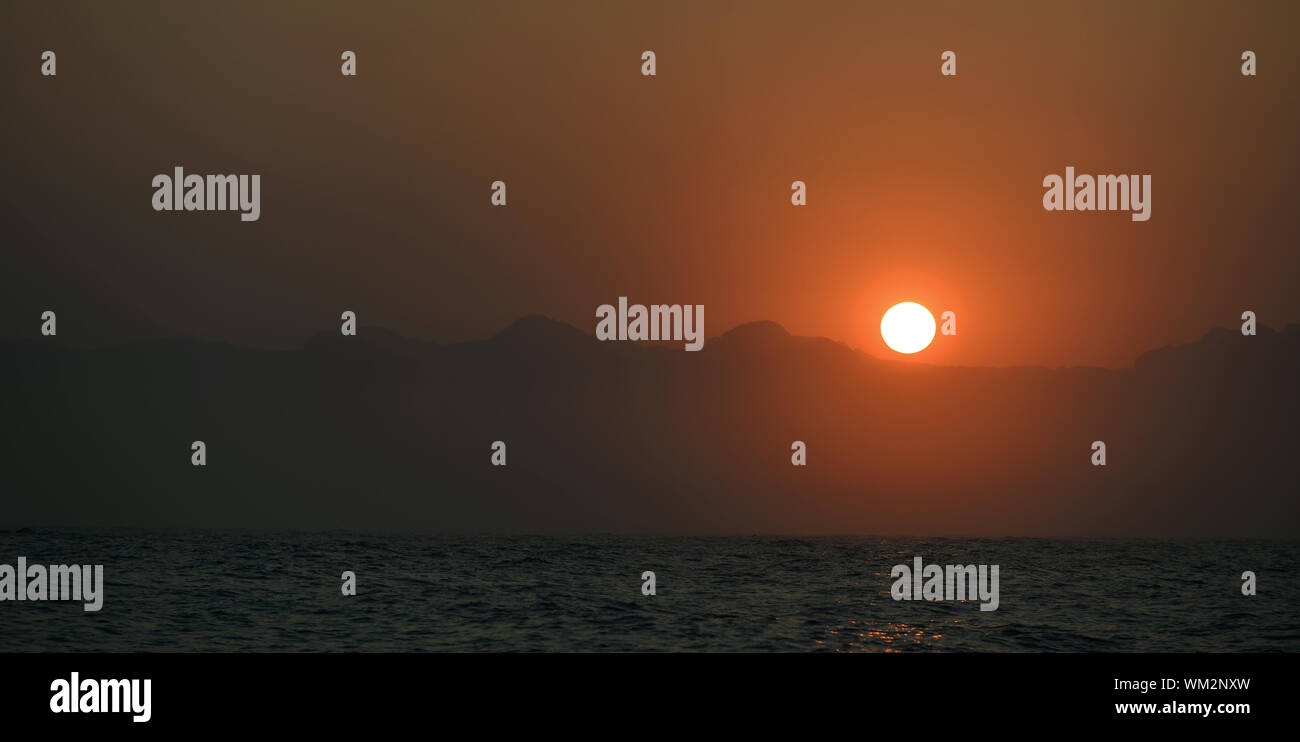 orange sunset at the ocean with mountains silhouettes. South Africa ...