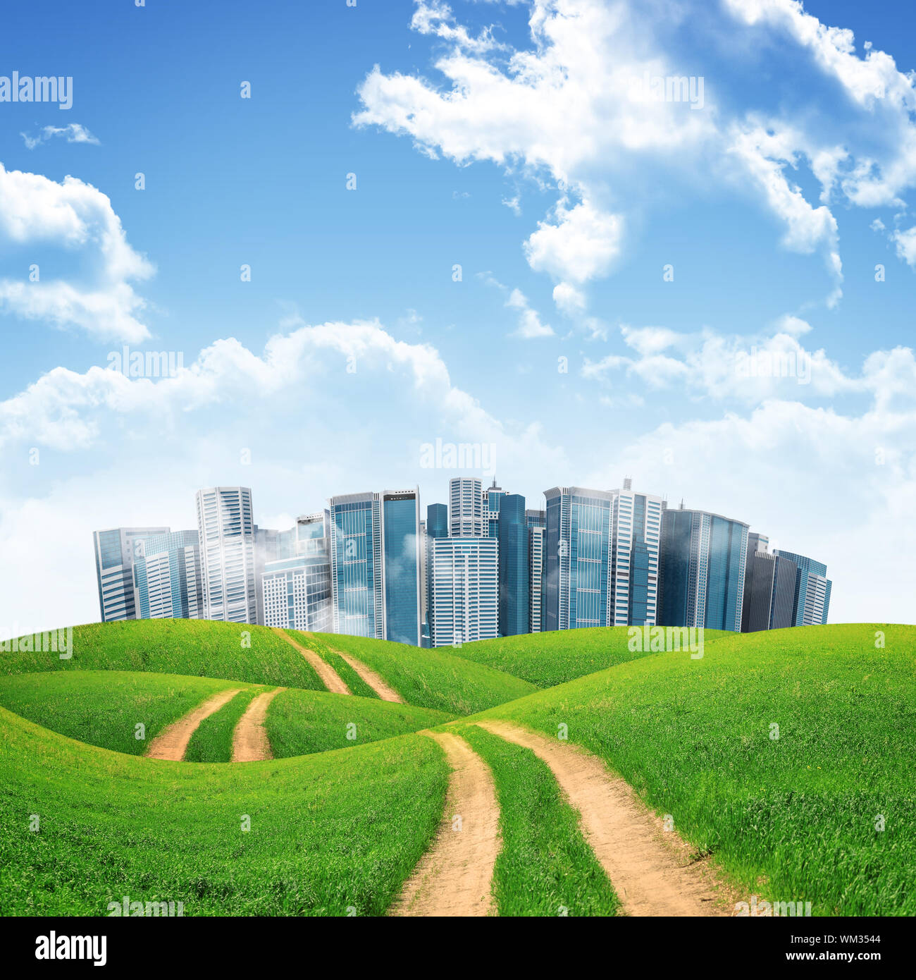Tall buildings, green hills and road against sky with clouds ...