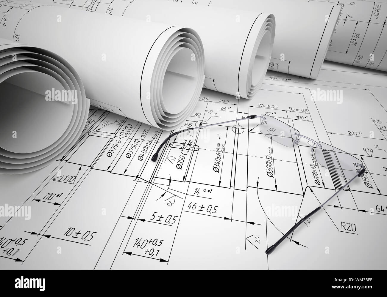 Scrolls of engineering drawings and glasses on drawing. Industrial ...