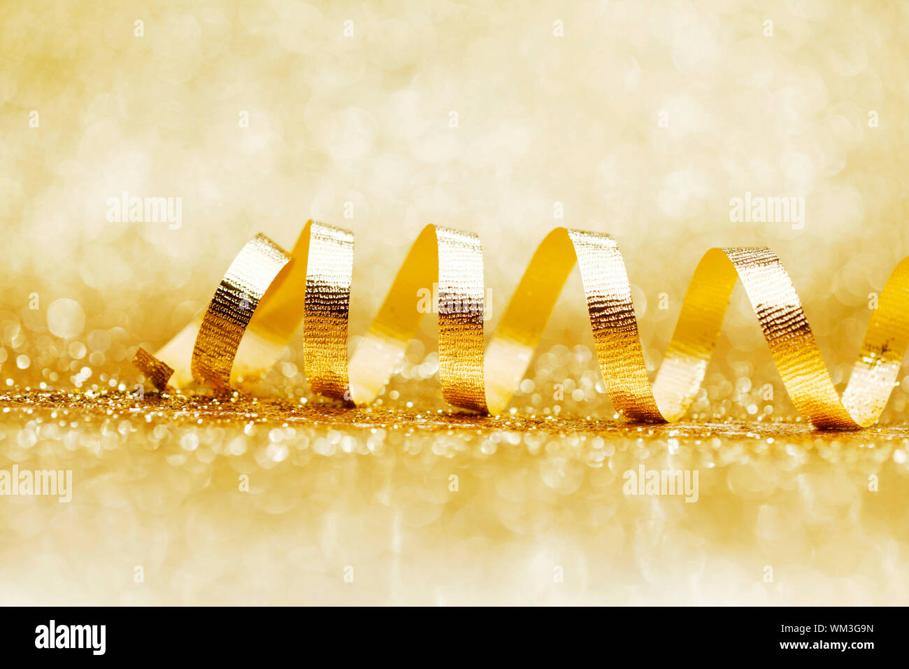 Golden curly ribbon decoration on glitter background close-up Stock ...