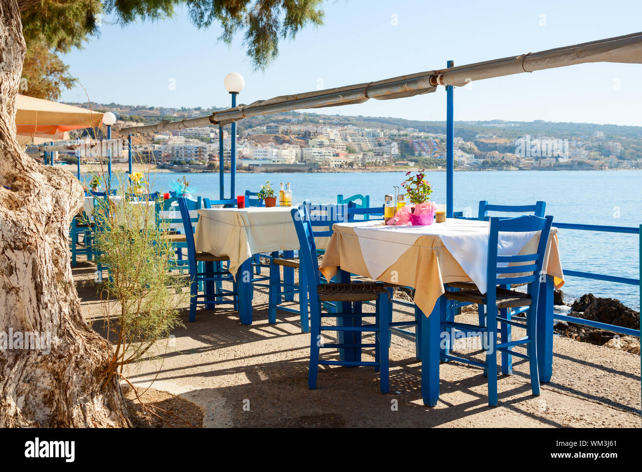 Empty greek cafe terrace in Heraklion, Crete overlooking the sea with ...