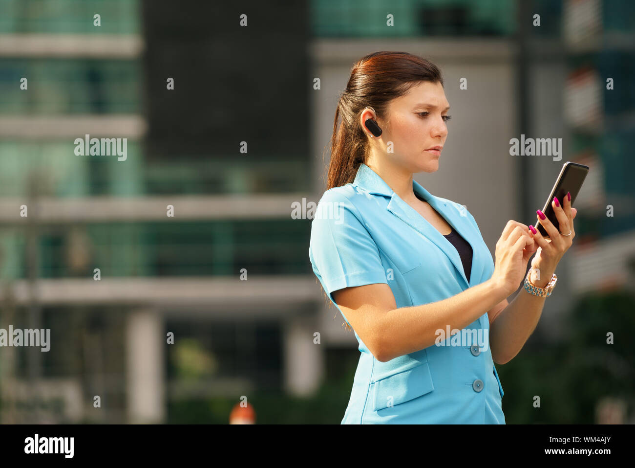 Adult hispanic person with mobile phone and wireless bluetooth headset ...