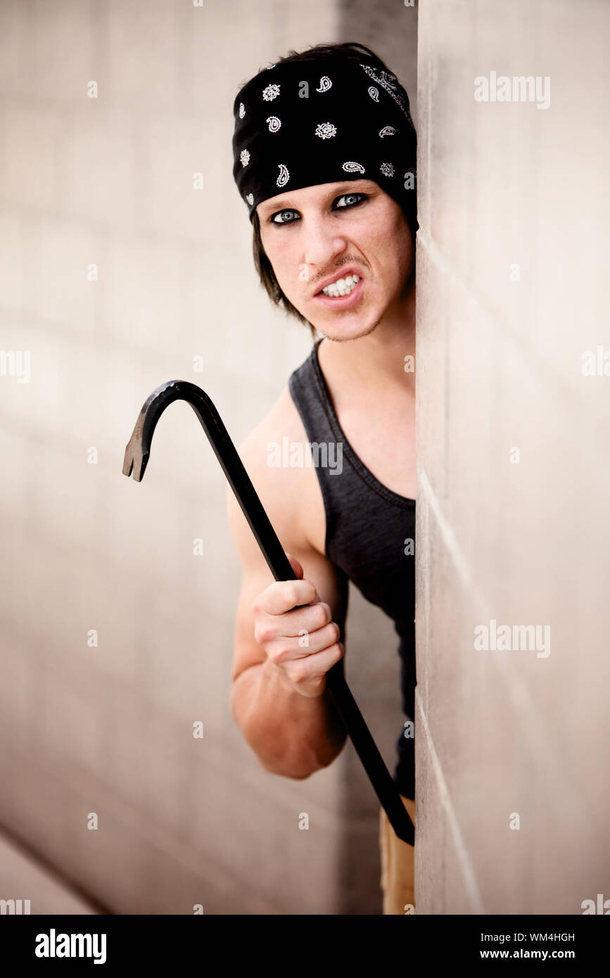 Criminal carrying a crowbar waiting to ambush victim Stock Photo - Alamy