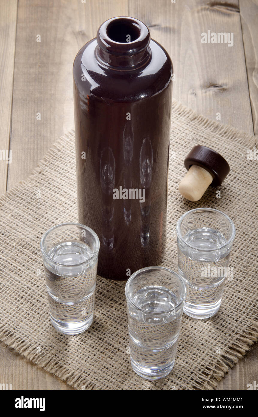 juniper brandy in small glasses and a dark bottle on jute Stock Photo ...