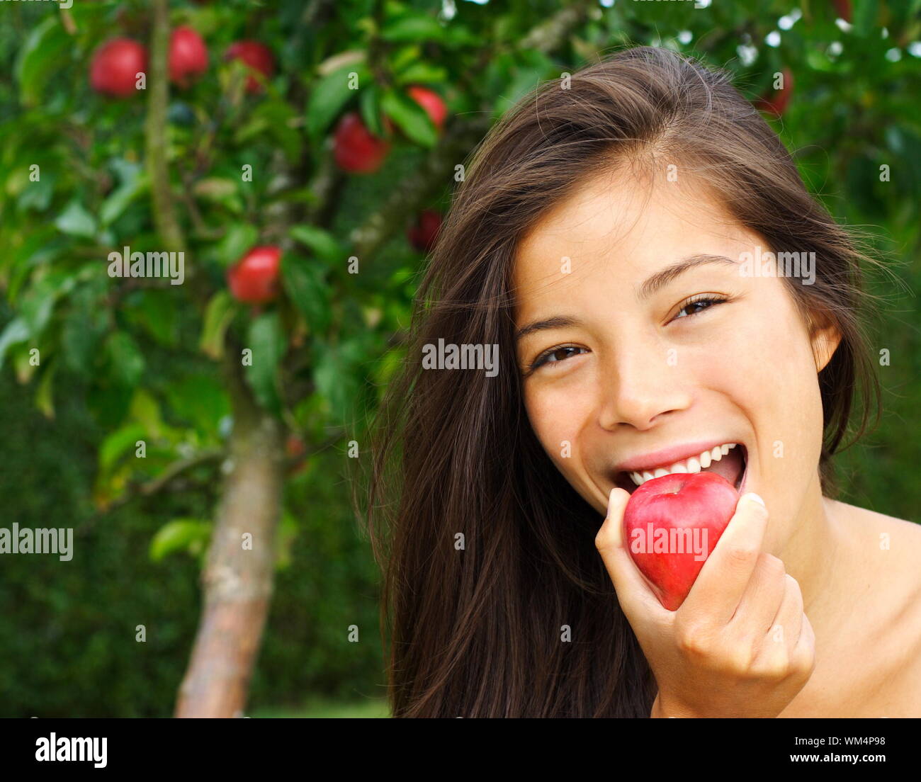 Apple woman. Very beautiful ethnic model eating red apple in the park ...