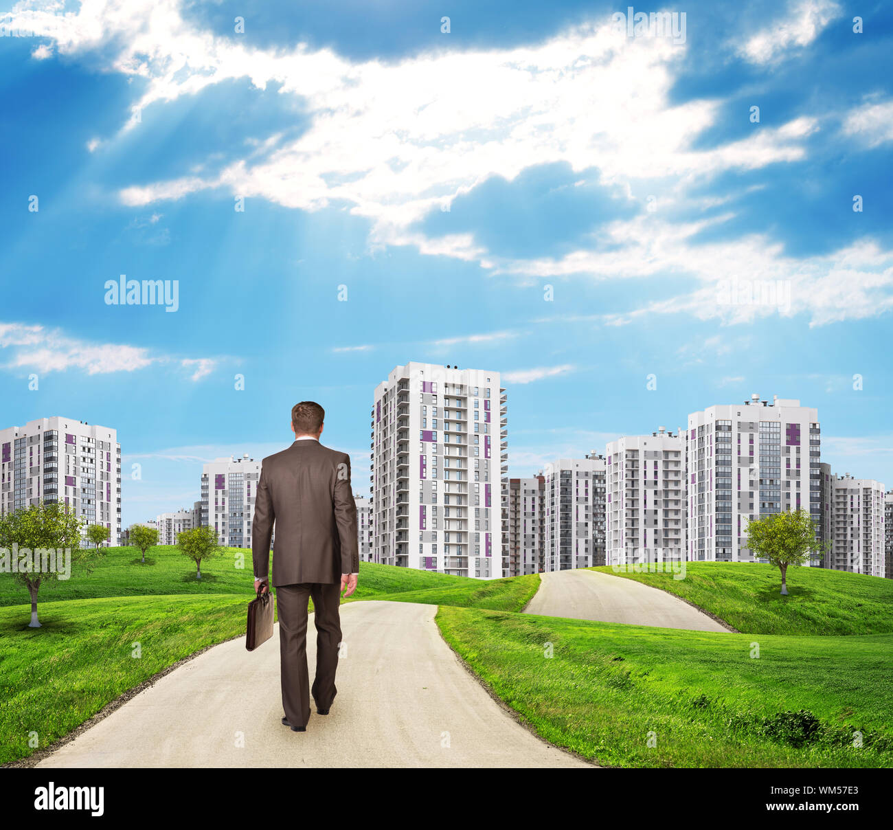 Businessman walking along road running through green hills with a few ...