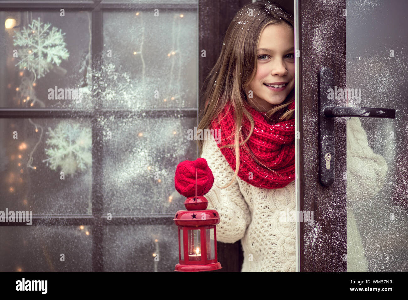 Child girl welcome guests and holding holiday lantern, snow weather ...