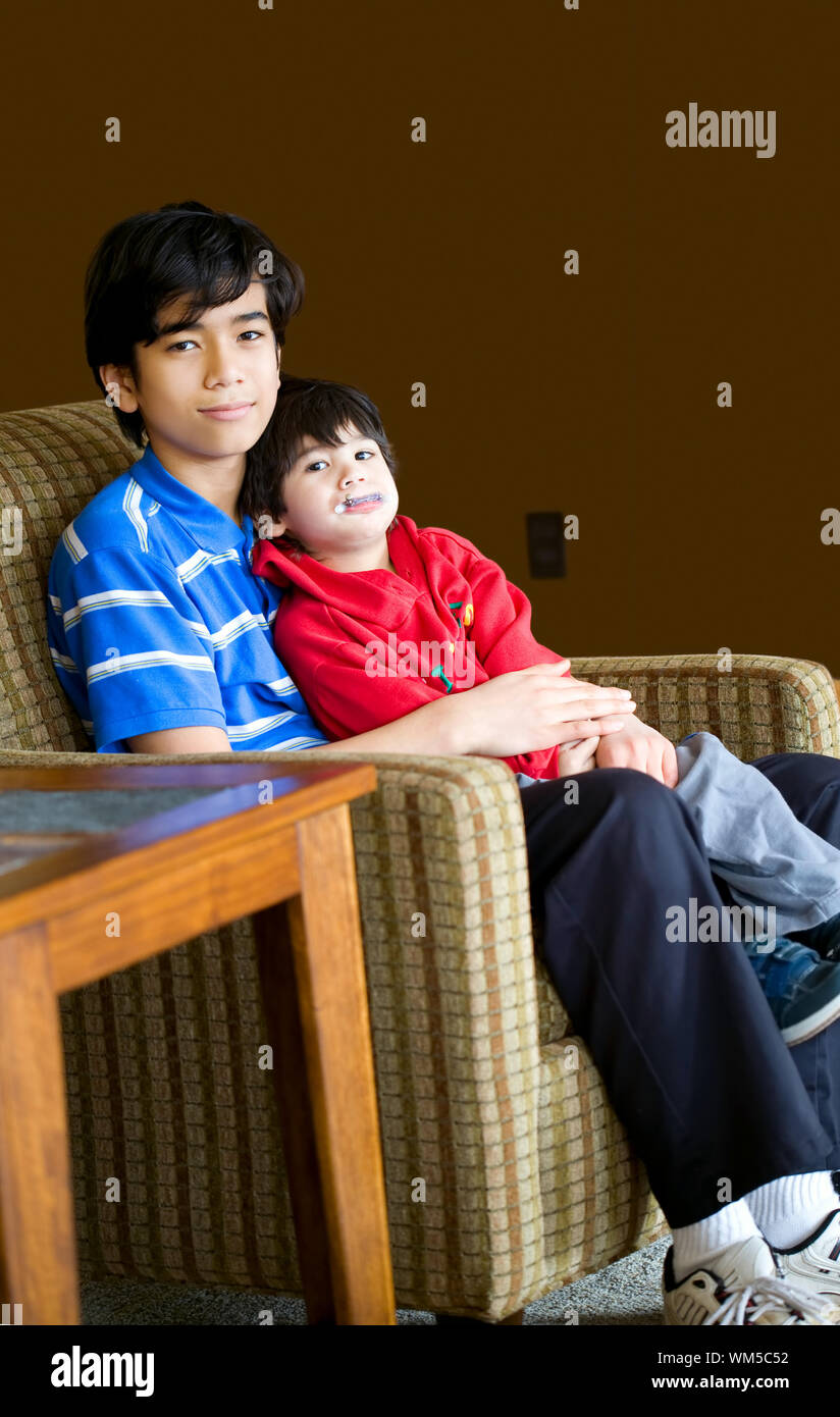 Big brother holding his younger disabled sibling Stock Photo - Alamy