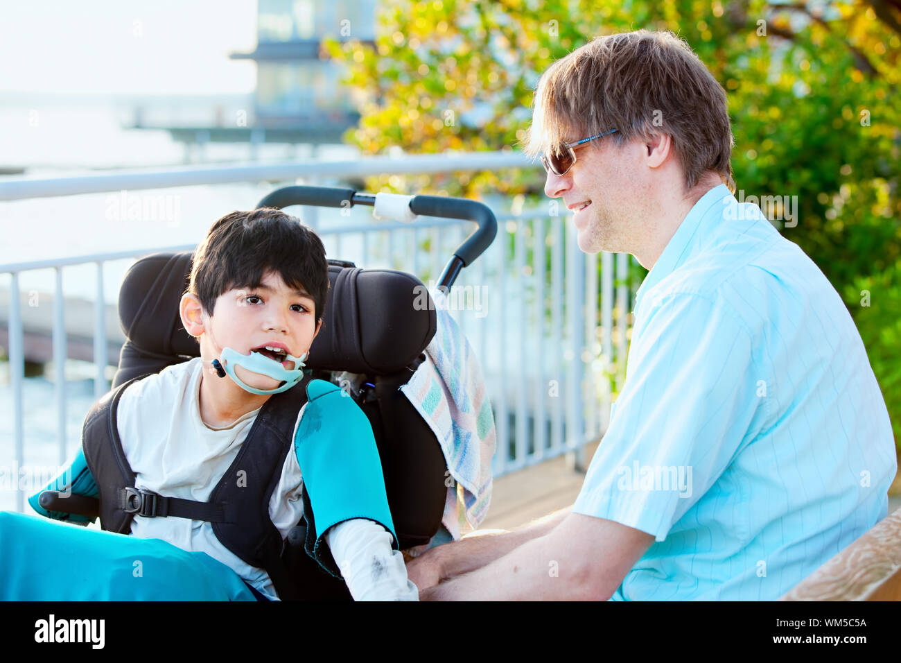 Father talking with his disabled son in wheelchair outdoors Stock Photo ...
