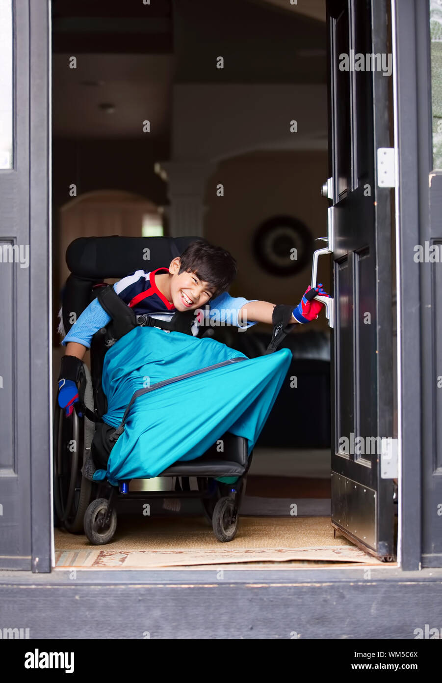 Smiling disabled boy in wheelchair opening front door Stock Photo - Alamy