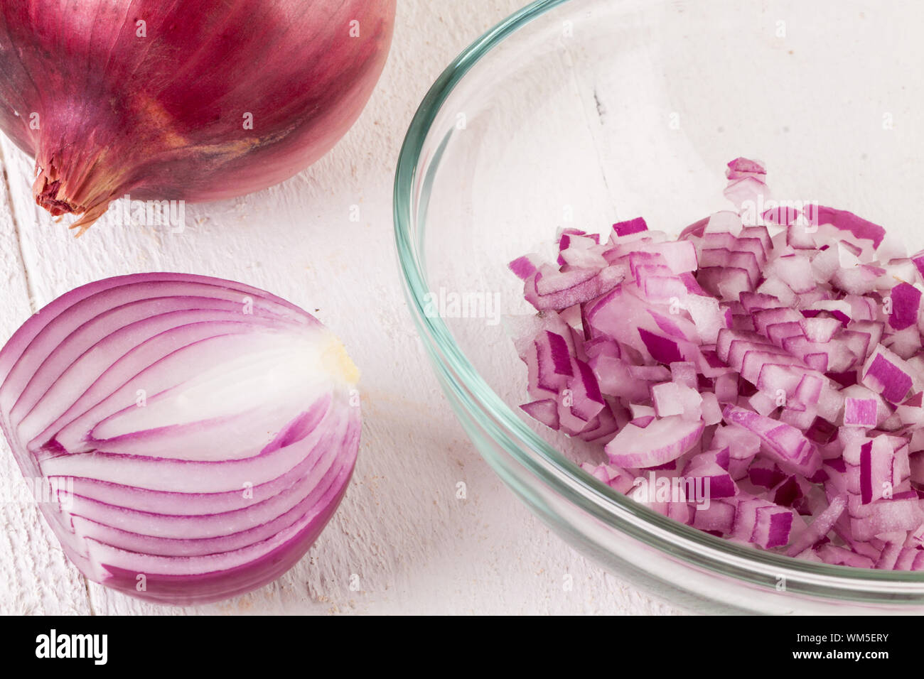 Heap of fresh finely diced red onion with a peeled half showing a cross ...