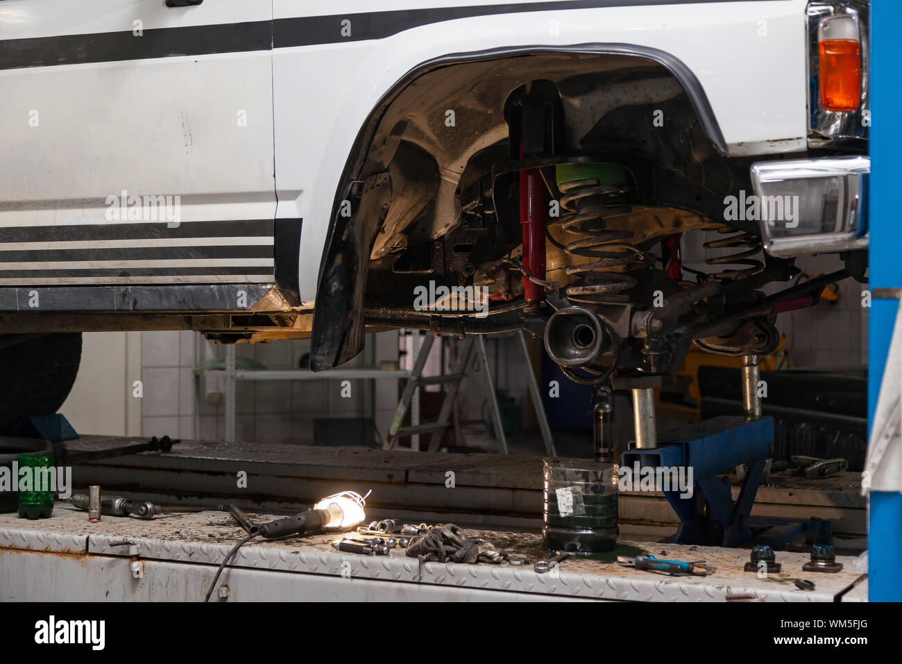 Car suspension repair in the back of a white SUV on a lift with a wheel ...
