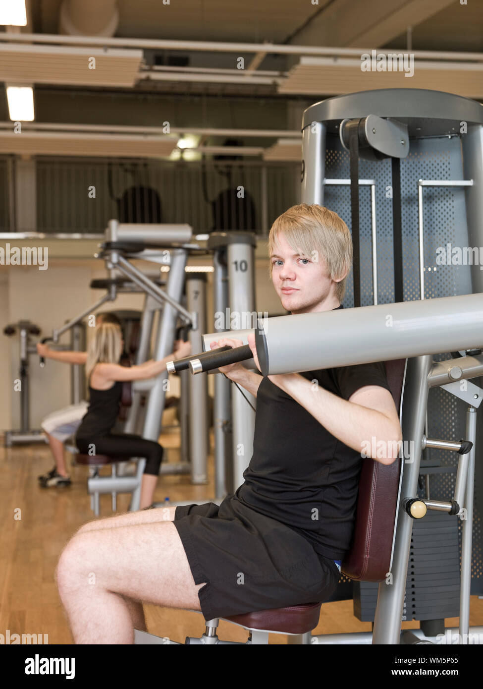 Young man using an exercise machine at a health club Stock Photo - Alamy