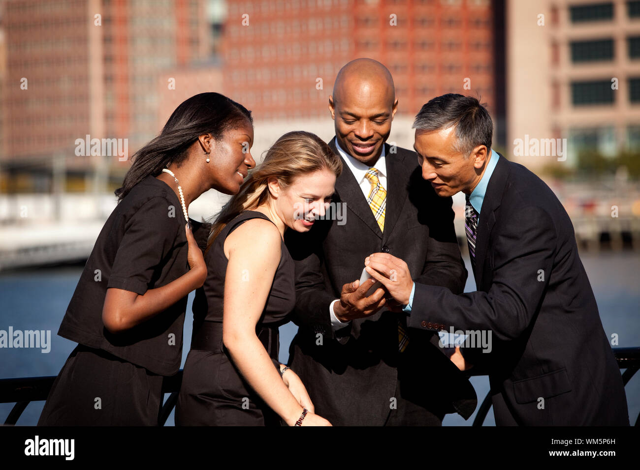 A group of business people crowded around a cell phone Stock Photo - Alamy