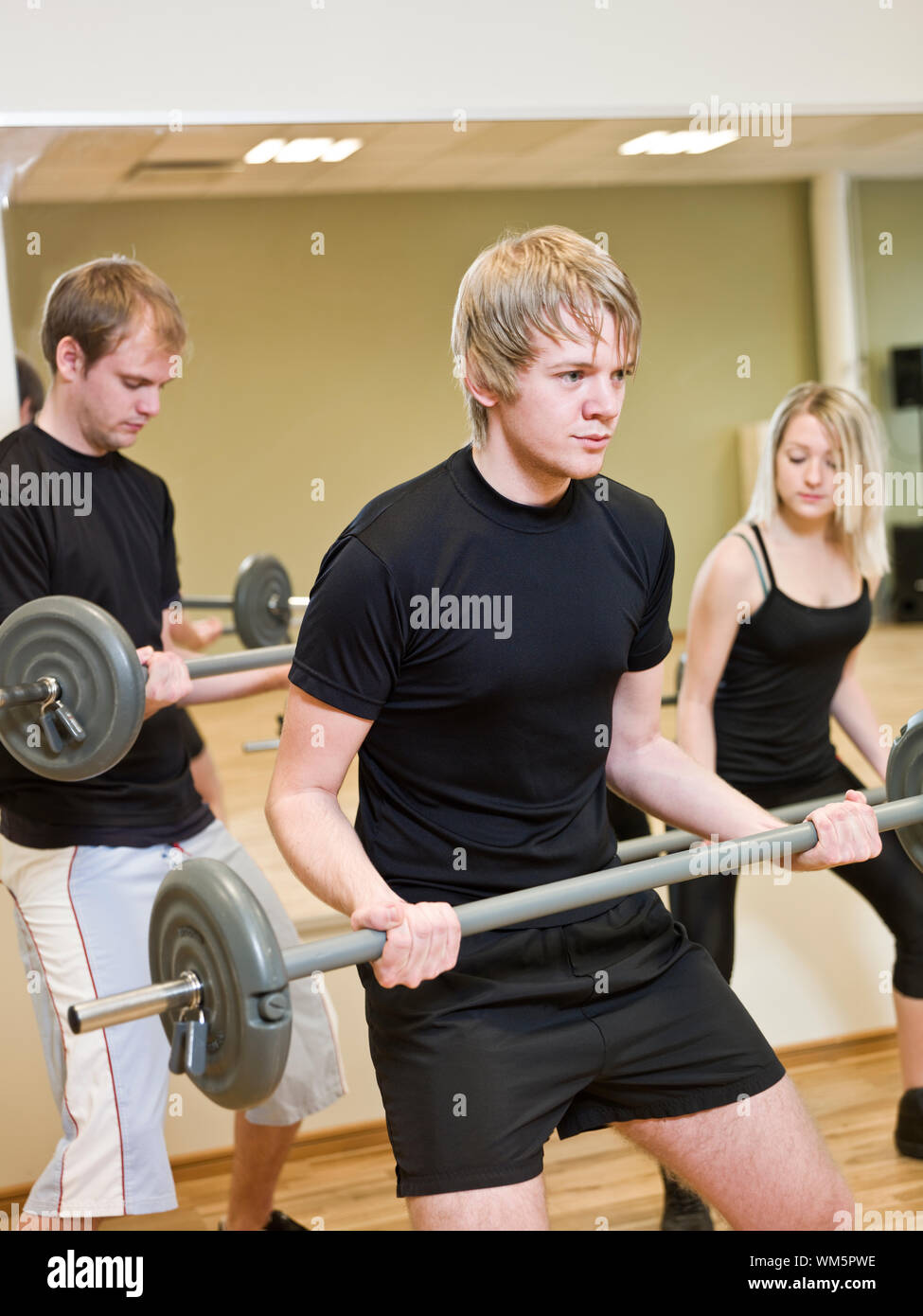 Group of people lifting weights with a young man in focus Stock Photo - Alamy