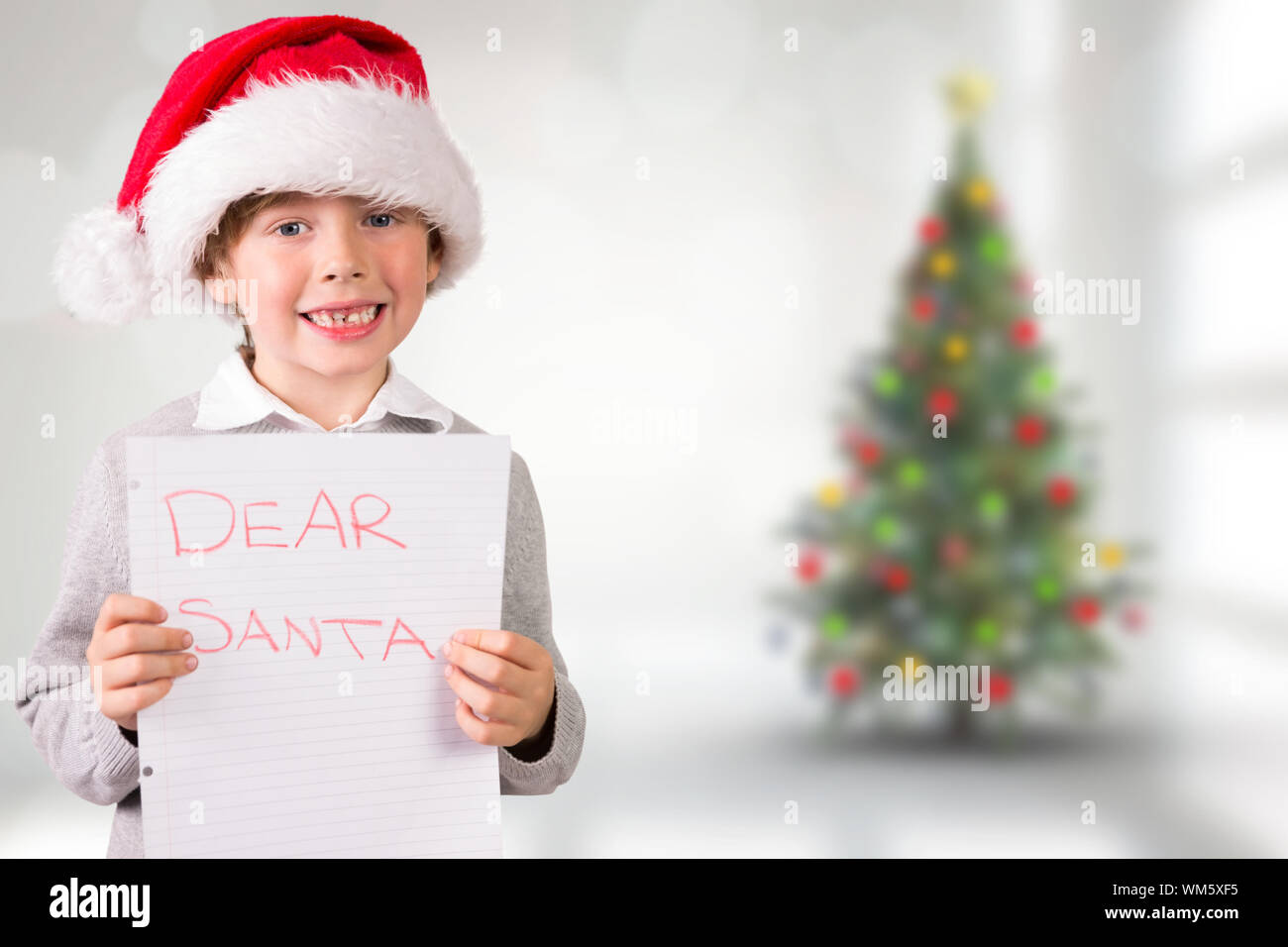 Festive boy showing letter against blurry christmas tree in room Stock ...