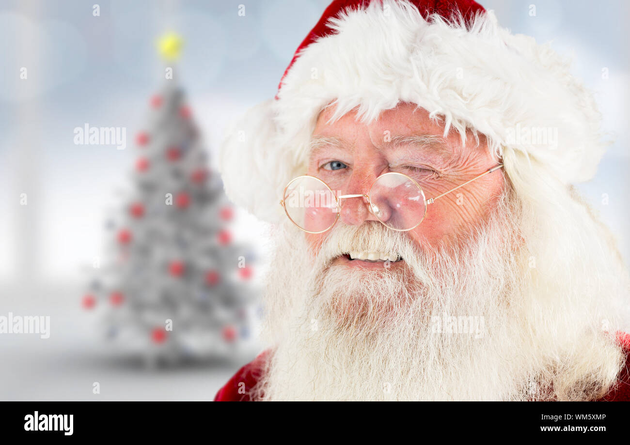 Santa claus winking against blurry christmas tree in room Stock Photo ...