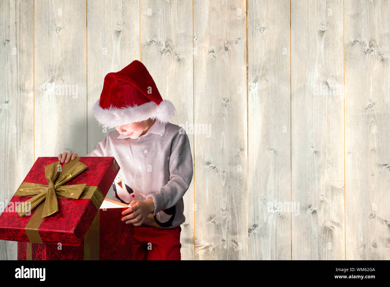 Festive boy opening gift against pale wooden planks Stock Photo - Alamy