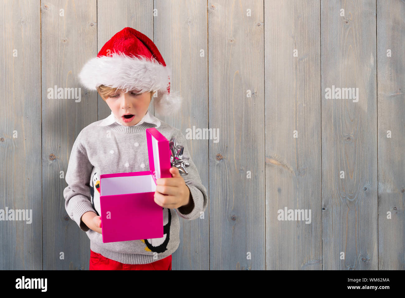 Festive boy holding a gift against pale grey wooden planks Stock Photo ...