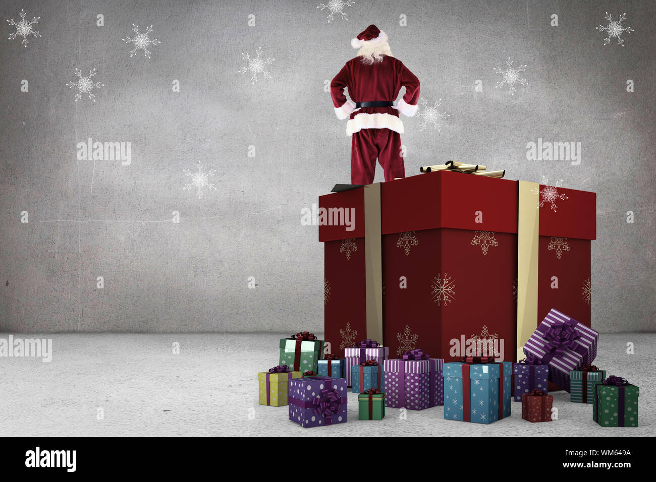 Santa standing on giant present against grey room Stock Photo - Alamy